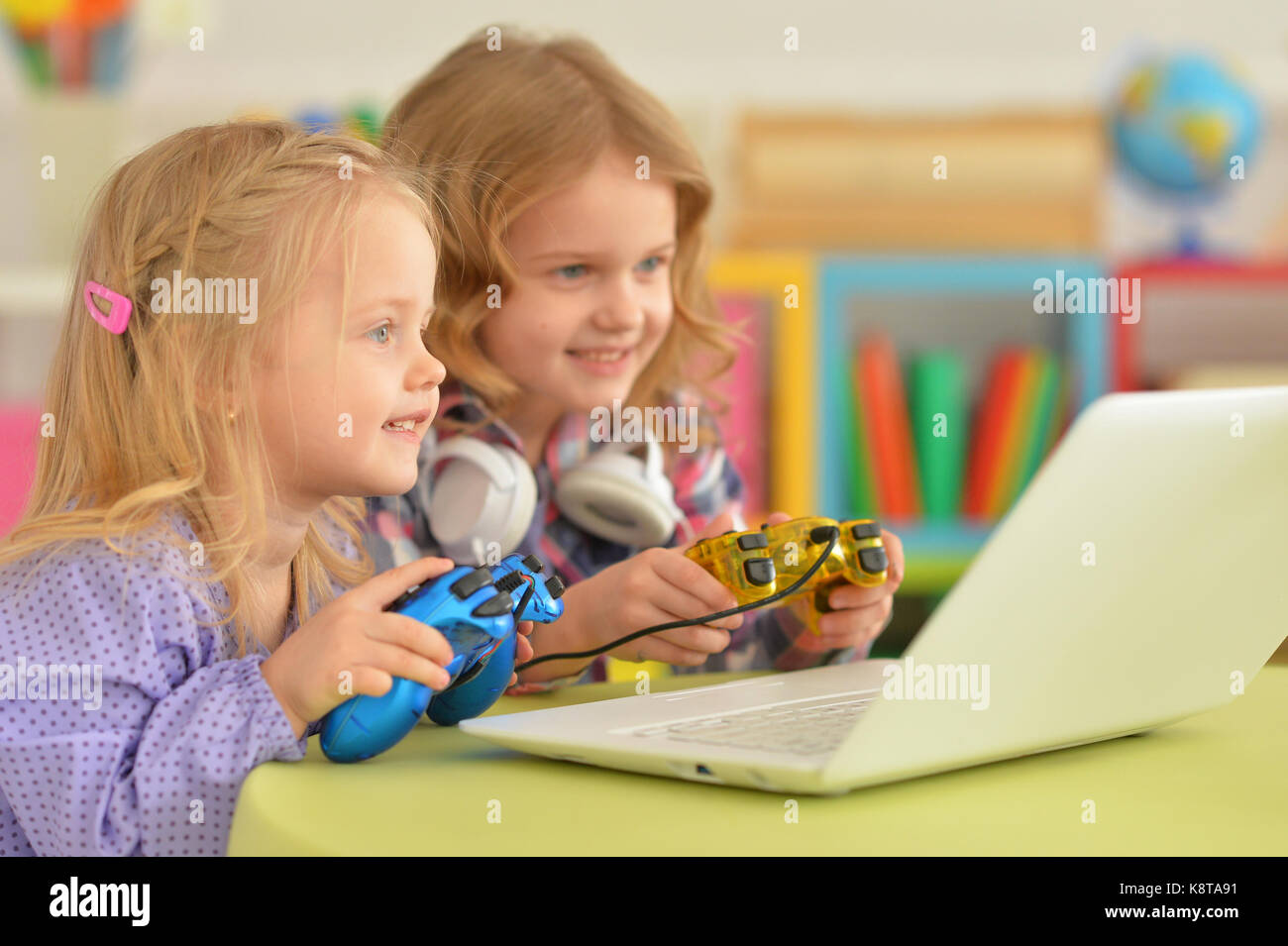 Cute little girls playing computer game on laptop Stock Photo - Alamy