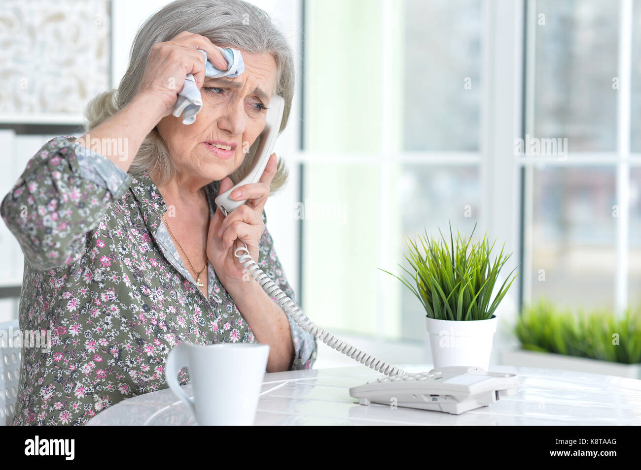 Senior woman with headache talking on phone Stock Photo - Alamy
