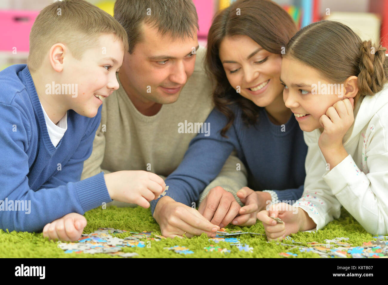 Parents and children lying on floor and collecting puzzle pieces Stock ...