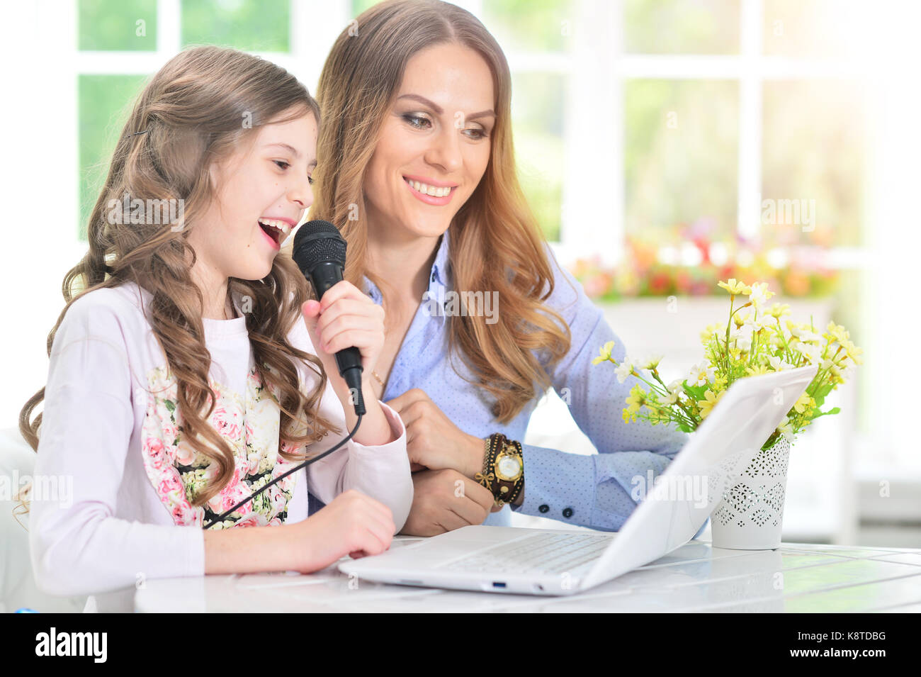 Beautiful young woman and girl sitting at table and using laptop ...
