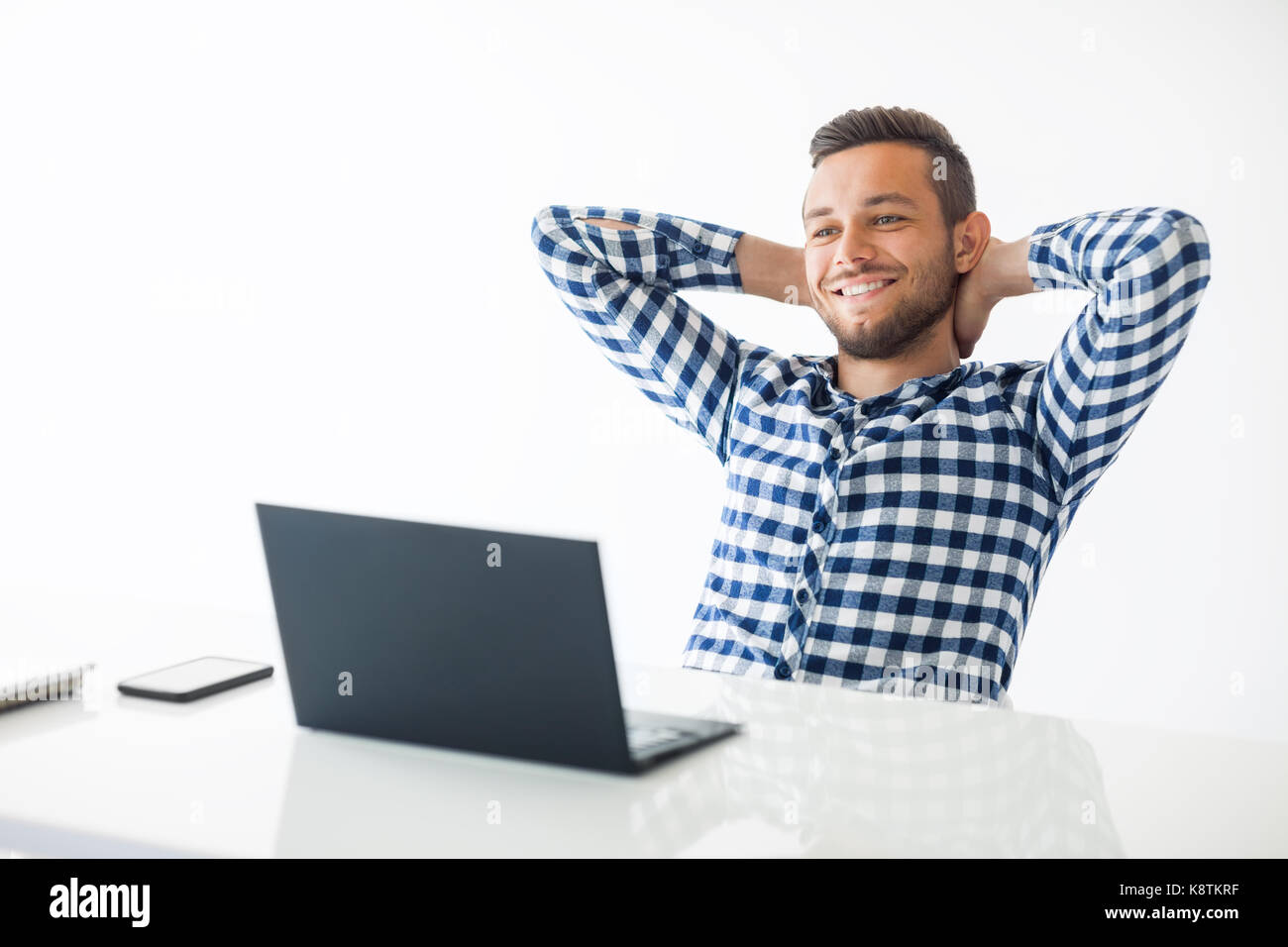 Relaxed happy man sitting with laptop on white background Stock Photo ...