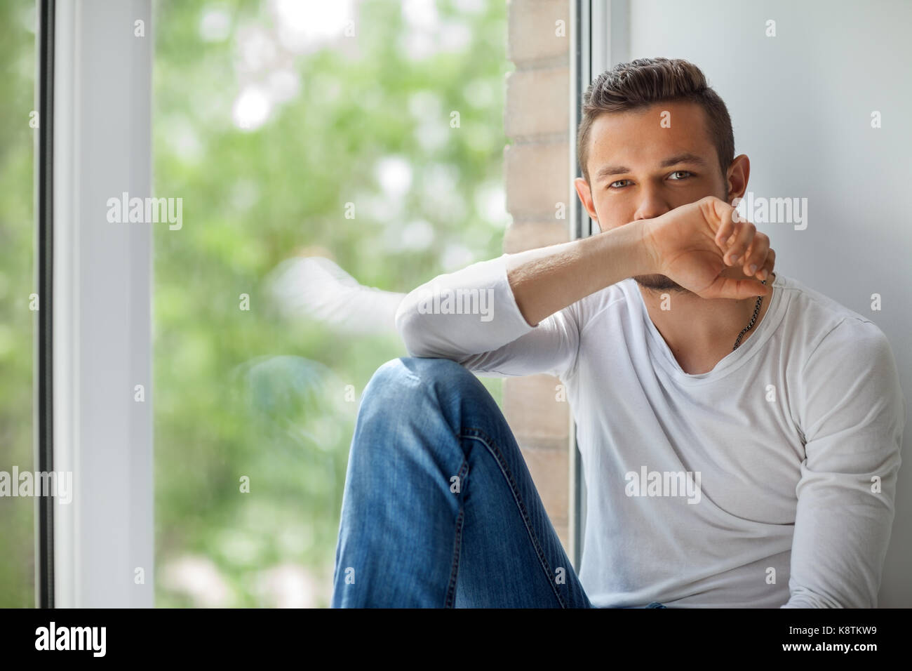 Shy handsome man close face with hand sitting on window sill Stock ...