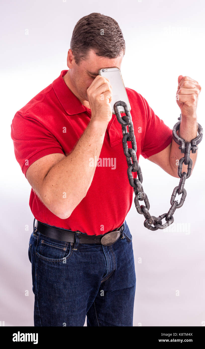 Adult man in distress, shackled to his cell phone. Man showing facial ...