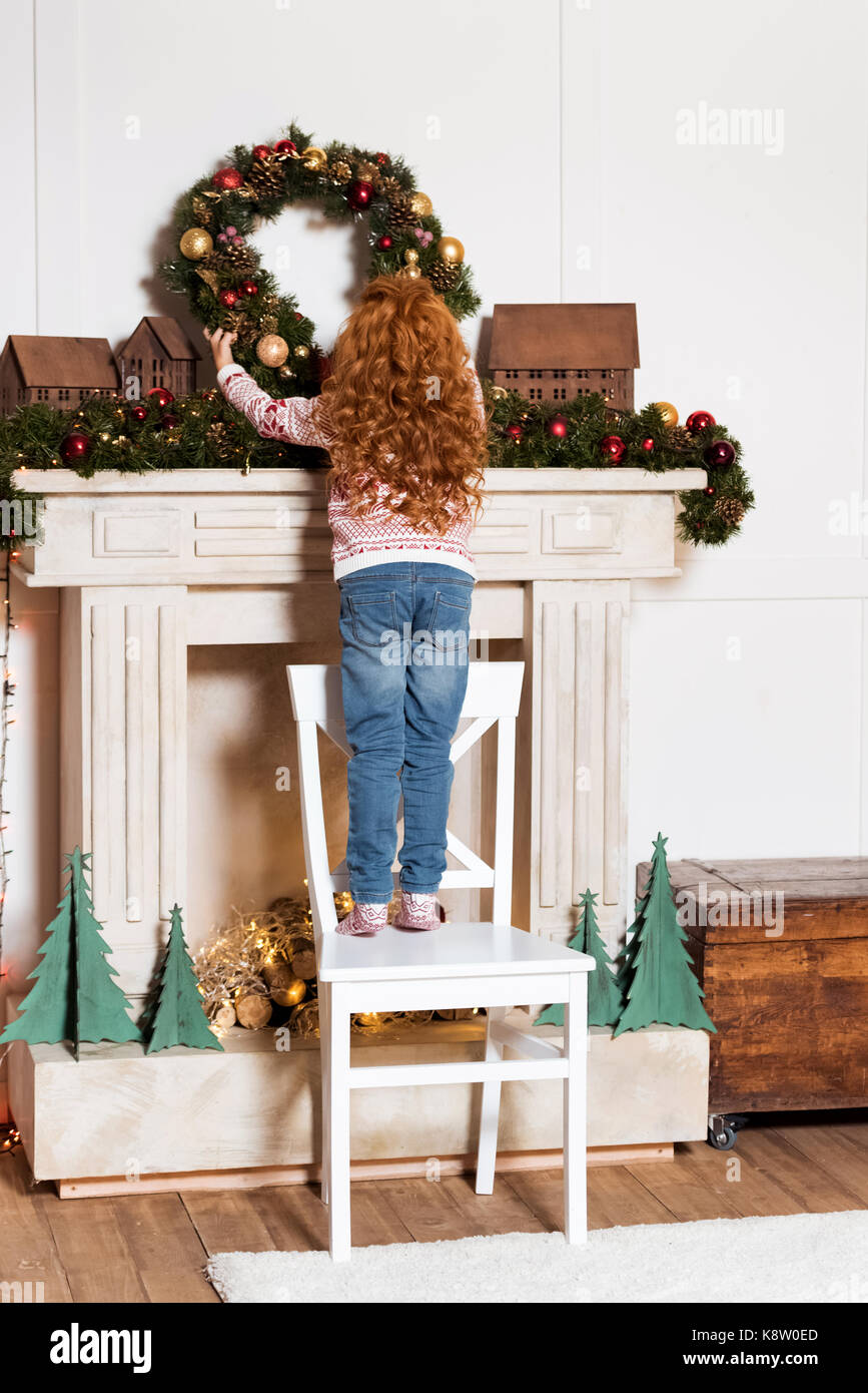 child hanging christmas wreath at home Stock Photo - Alamy