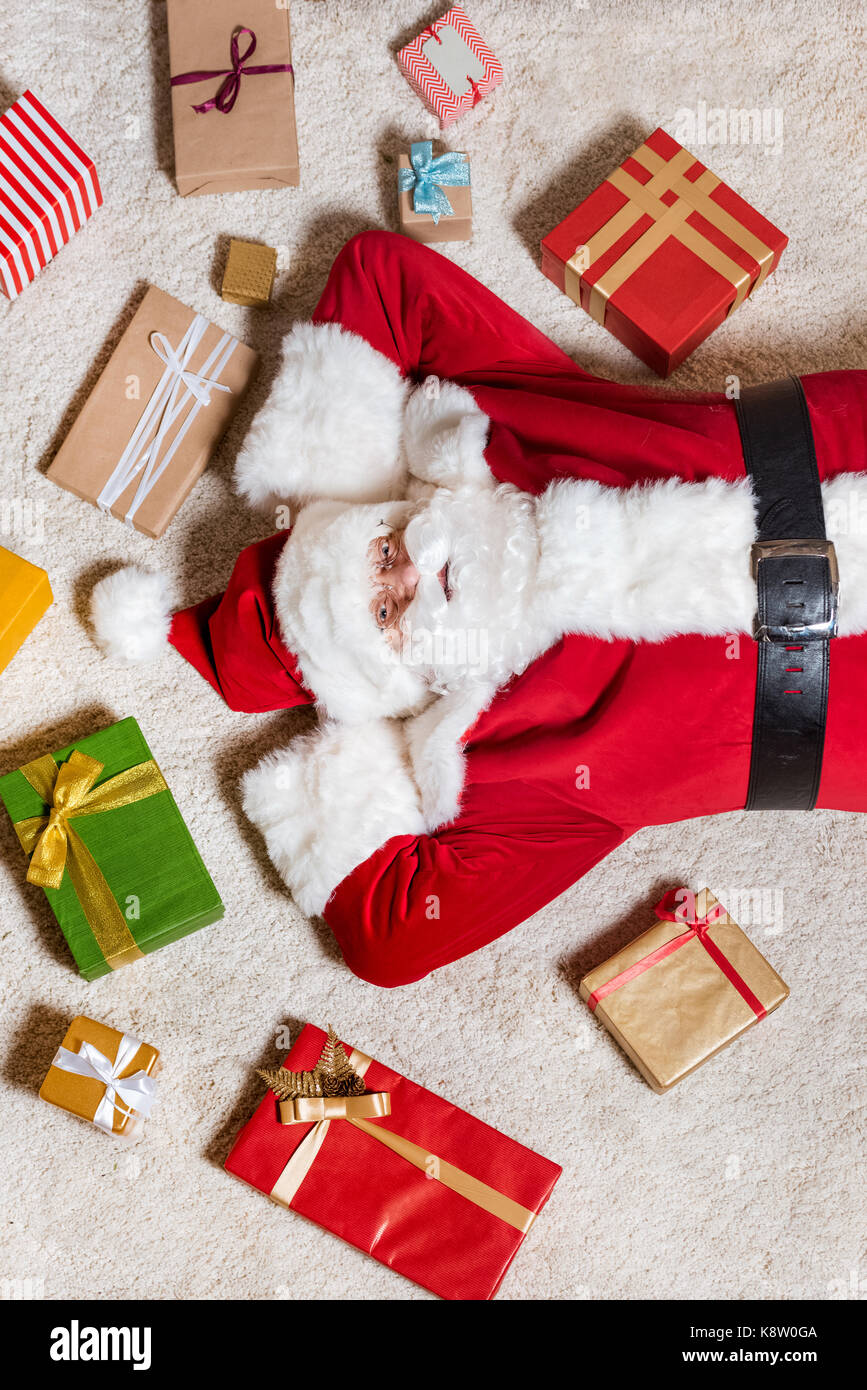 santa claus lying on floor with presents Stock Photo - Alamy