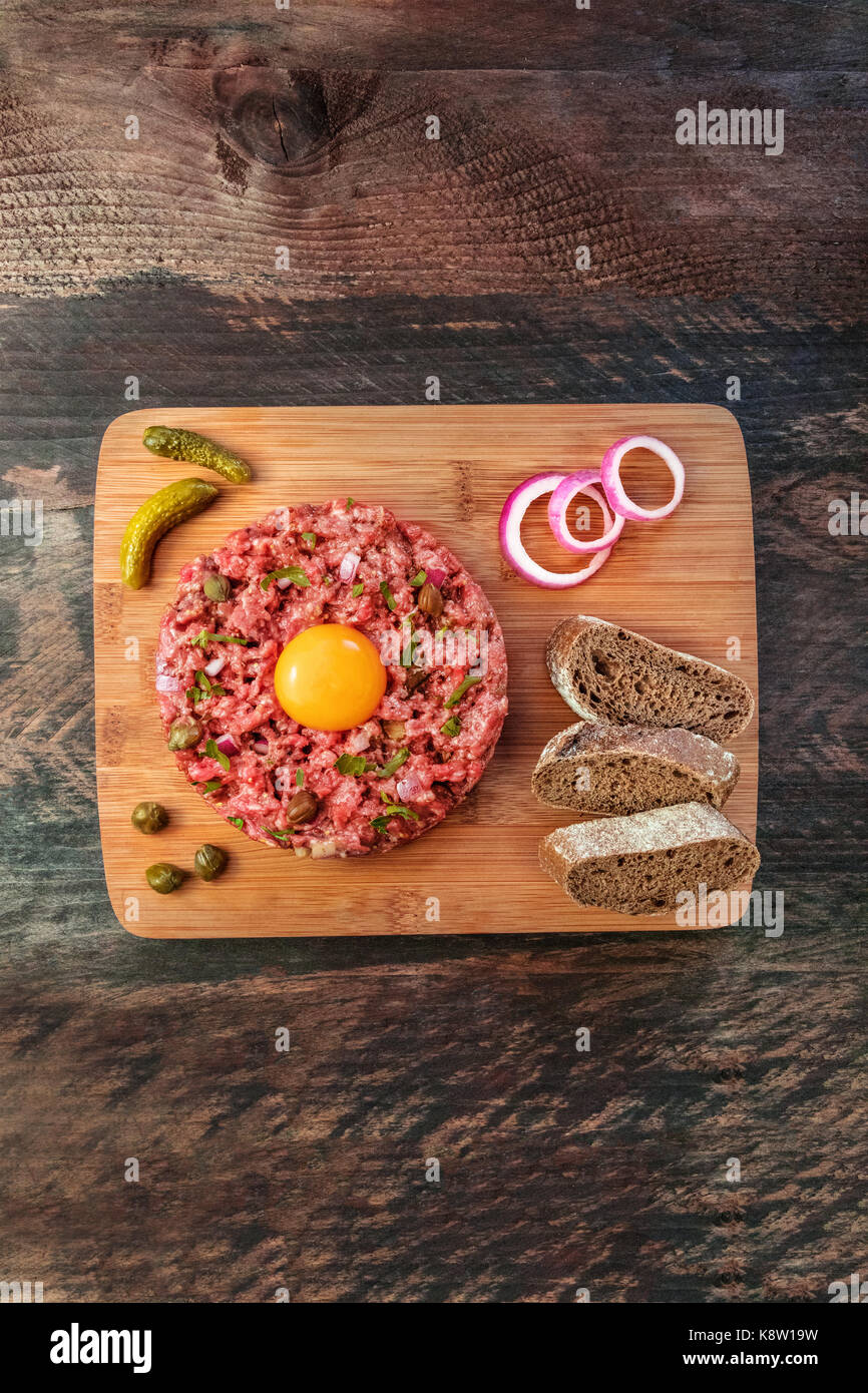 An overhead photo of a steak tartare with a raw egg yolk, rye bread ...