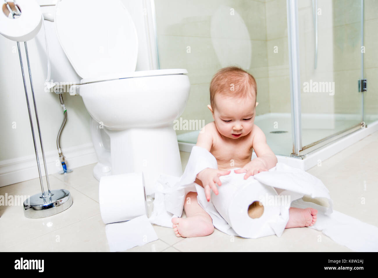 Toddler ripping up toilet paper in bathroom Stock Photo - Alamy