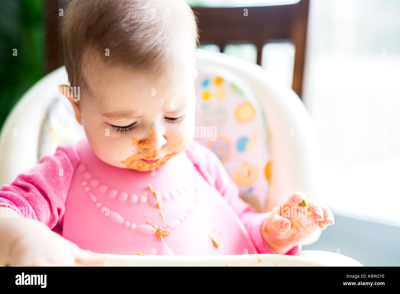 Adorable baby girl making a mess while feeding herself Stock Photo - Alamy
