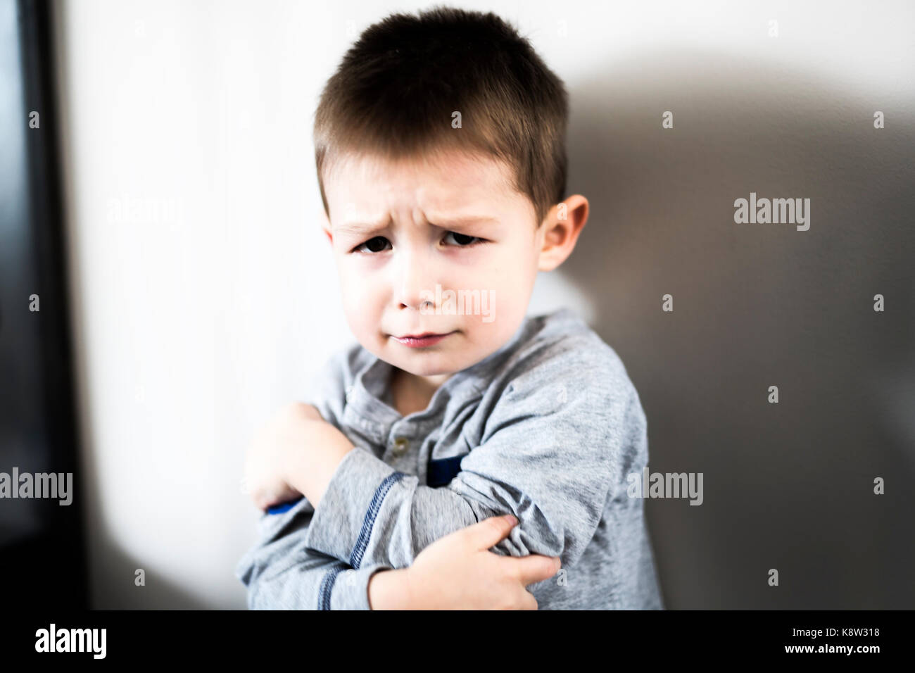 Boy sitting alone leaning on the wall Stock Photo - Alamy