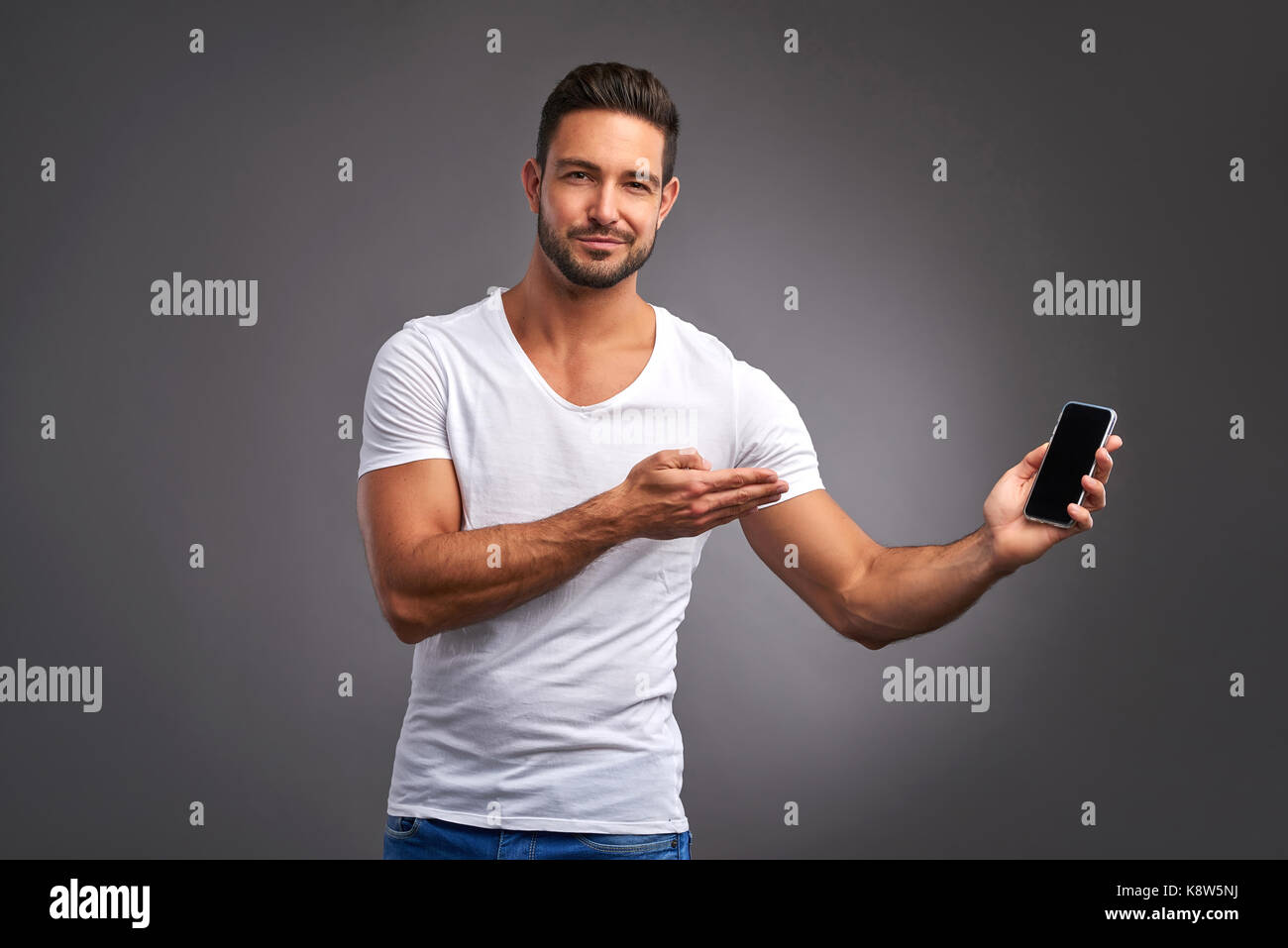 A confident handsome young man showing his phone to the camera Stock ...