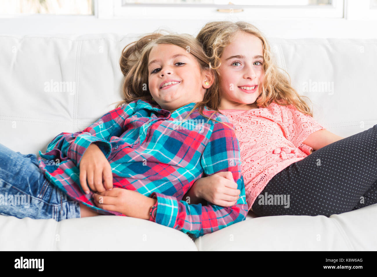 happy little girls lay on sofa Stock Photo - Alamy