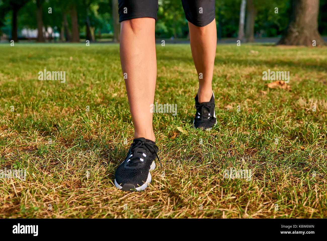 Close up of the legs of a young woman who is running off road in a park ...