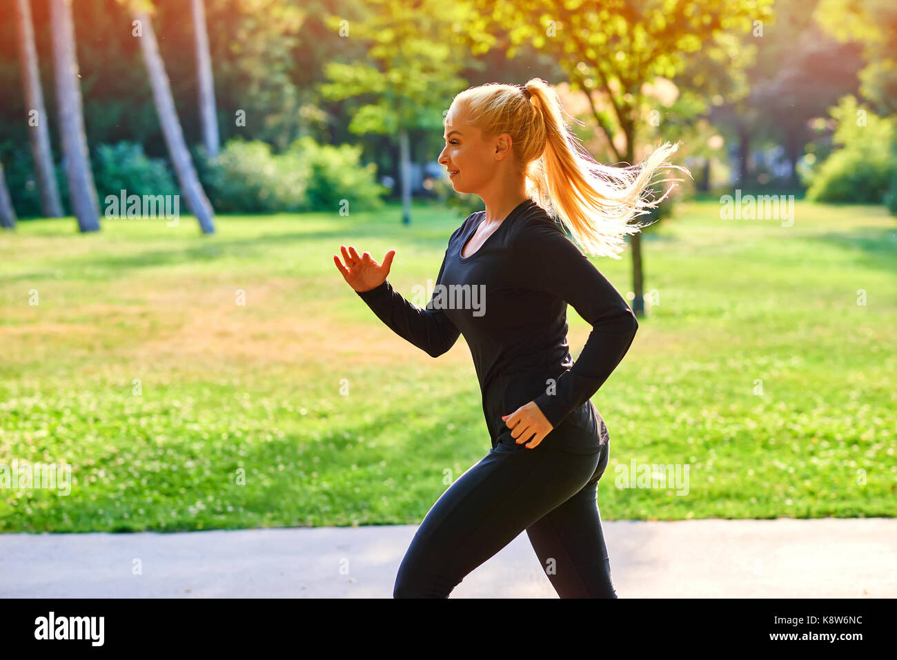 A beautiful young blonde woman wearing black clothes while running in a ...