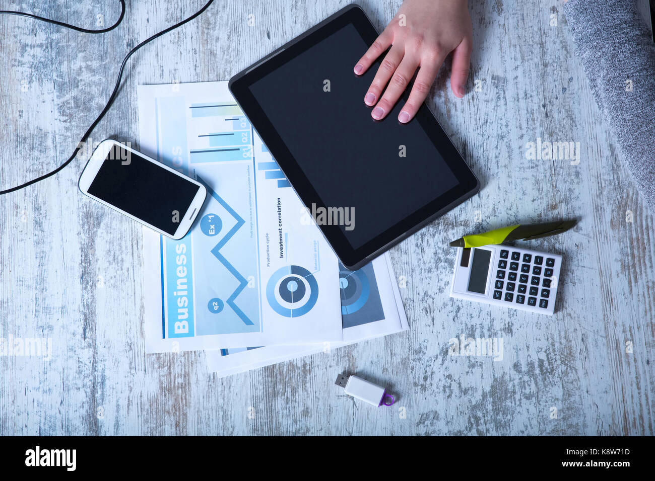 A working woman’s hand at night at a table with laptop, tablet and ...