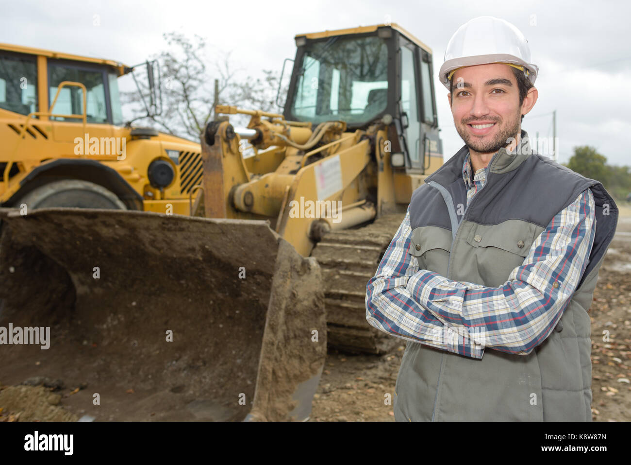 man posing next to the backhoe Stock Photo - Alamy