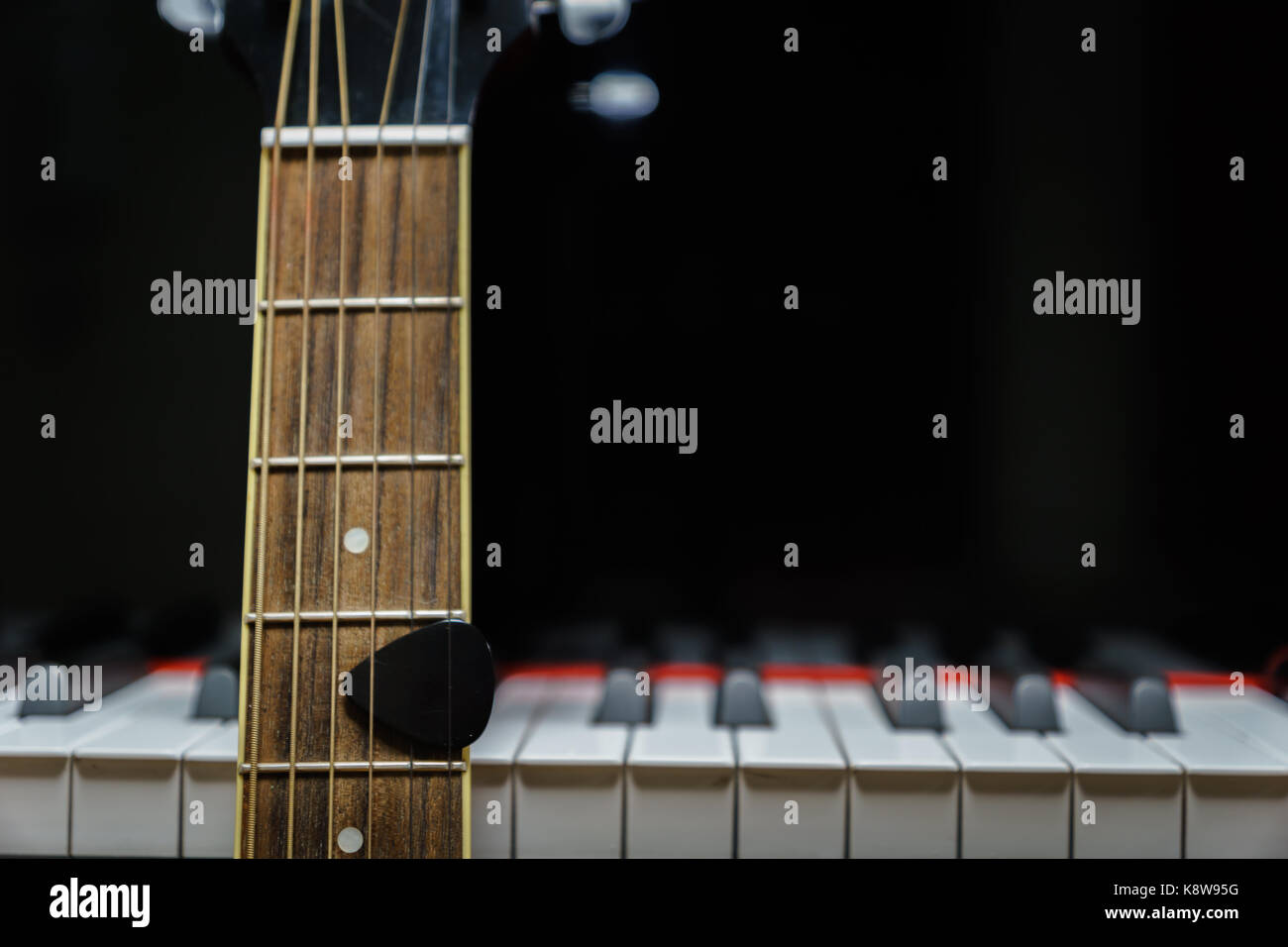 acoustic guitar against grand piano keys with plectrum - musical ...