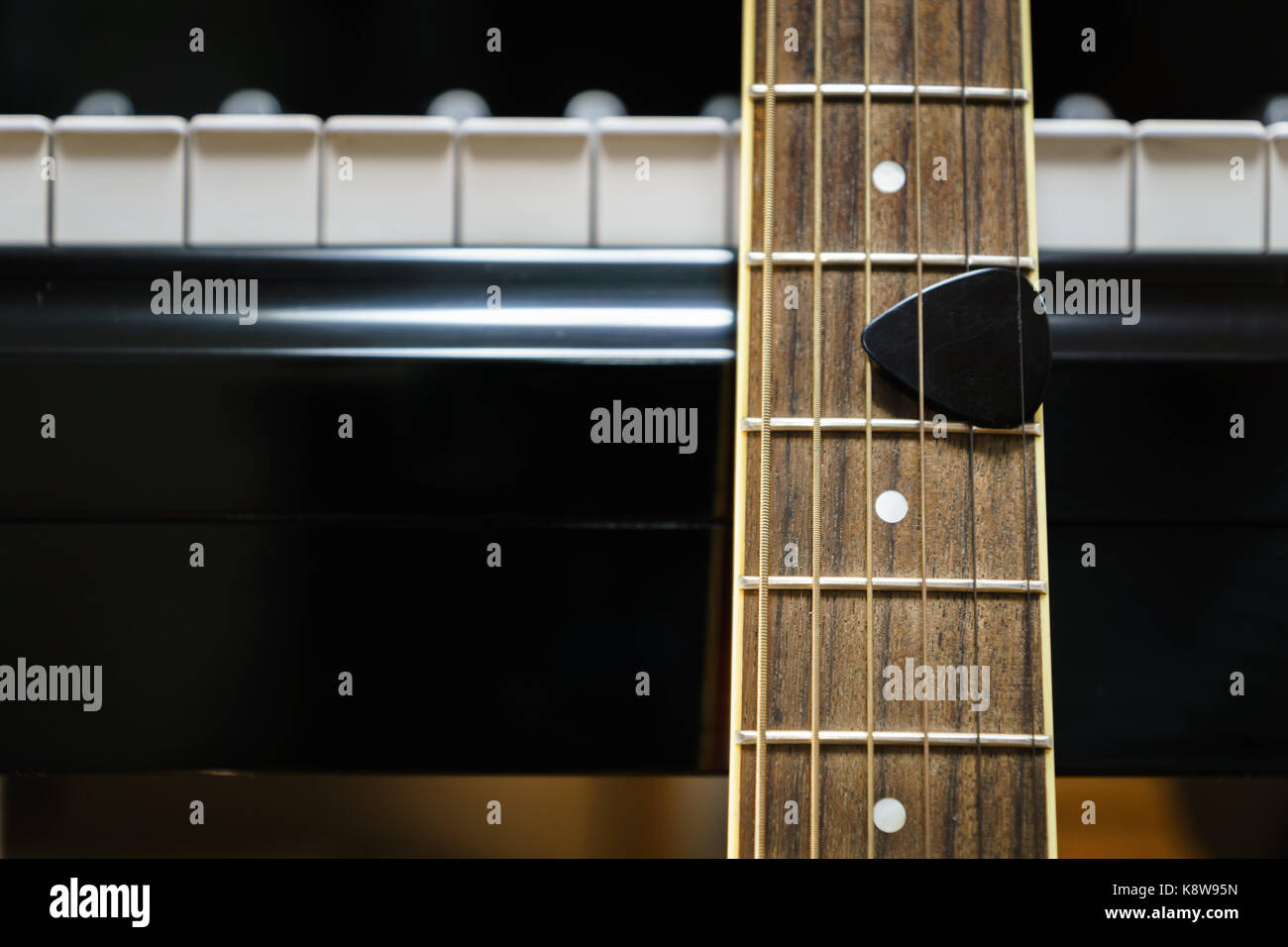 acoustic guitar against grand piano keys with plectrum - musical ...
