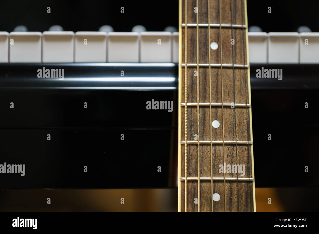 acoustic guitar against grand piano keys - musical instruments closeup ...