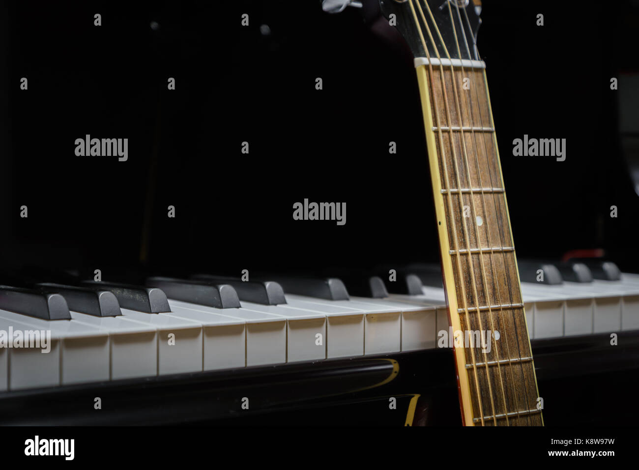 acoustic guitar against grand piano keys - musical instruments closeup ...