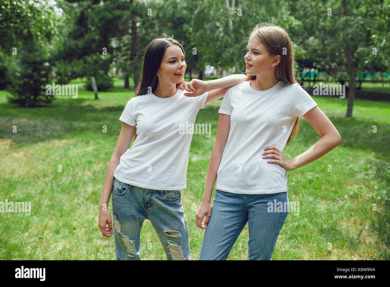 Girls in white T-shirts walking in the park. Mock up Stock Photo - Alamy