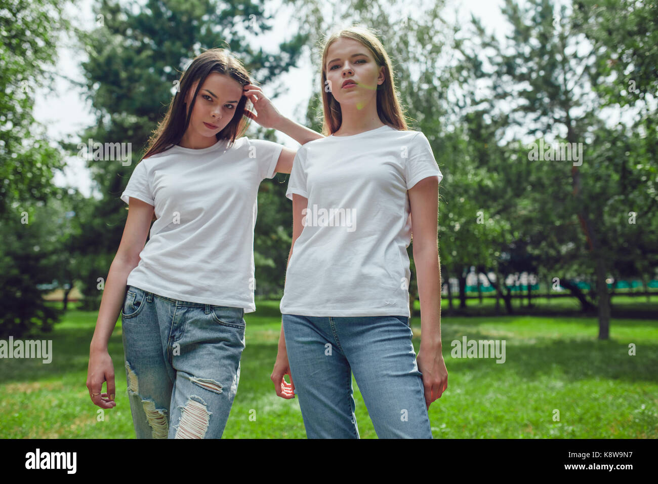 Girls in white T-shirts walking in the park. Mock up Stock Photo - Alamy