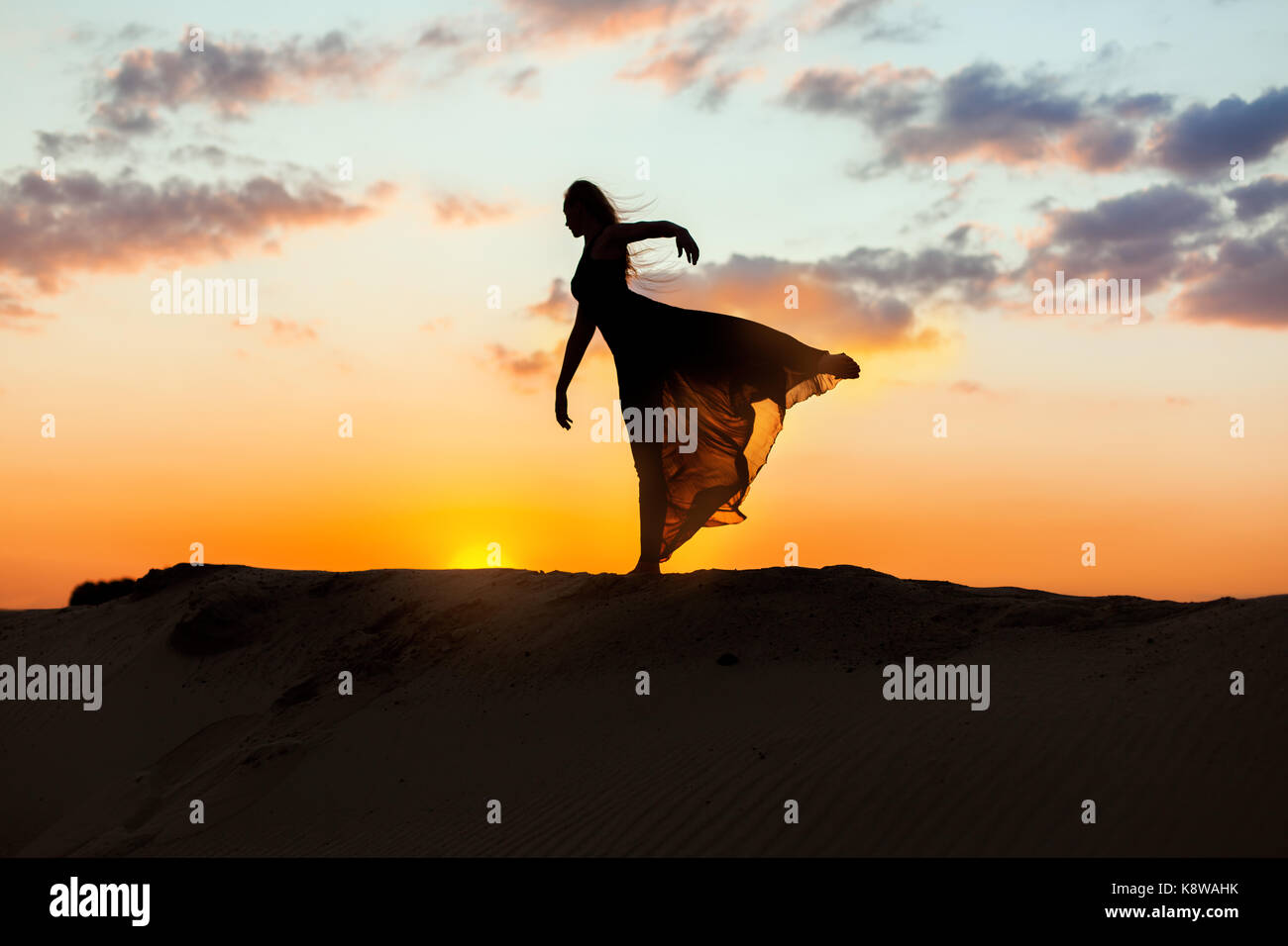 Female dancer dances at sunset, her dress is fluttering and translucent ...