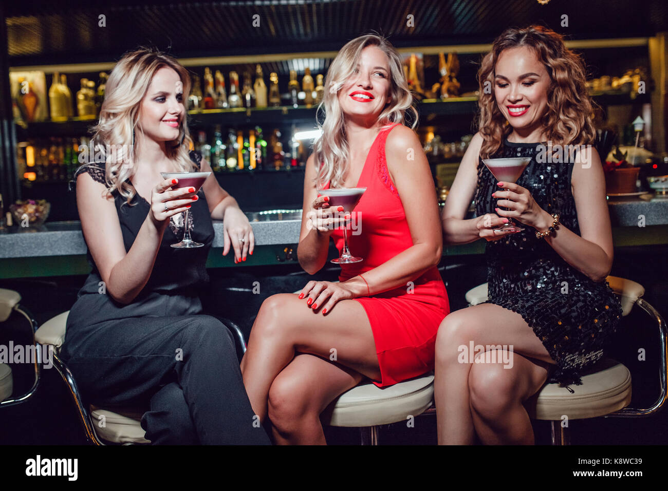 Beautiful women are sitting on the bar and drinking cocktails Stock ...