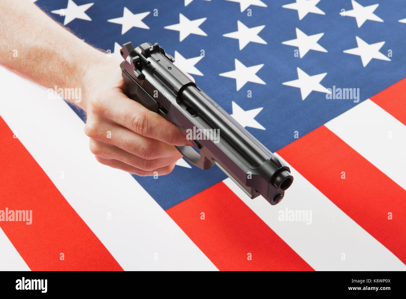 Male hand holding a handgun above satin USA flag - studio shoot Stock ...