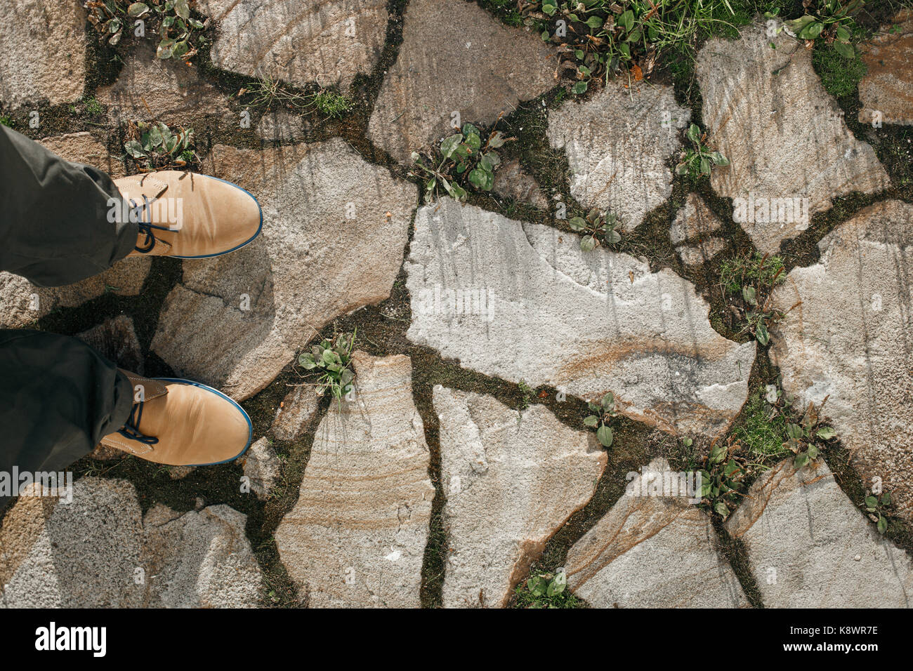 Male feet standing on the paved street in beige shoes. Top view Stock ...