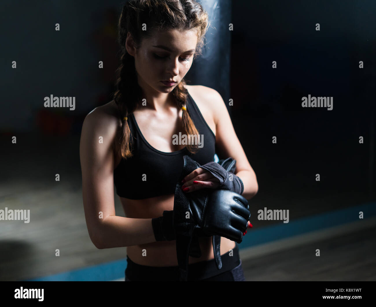 Young fighter boxer model girl putting on boxing gloves before training ...