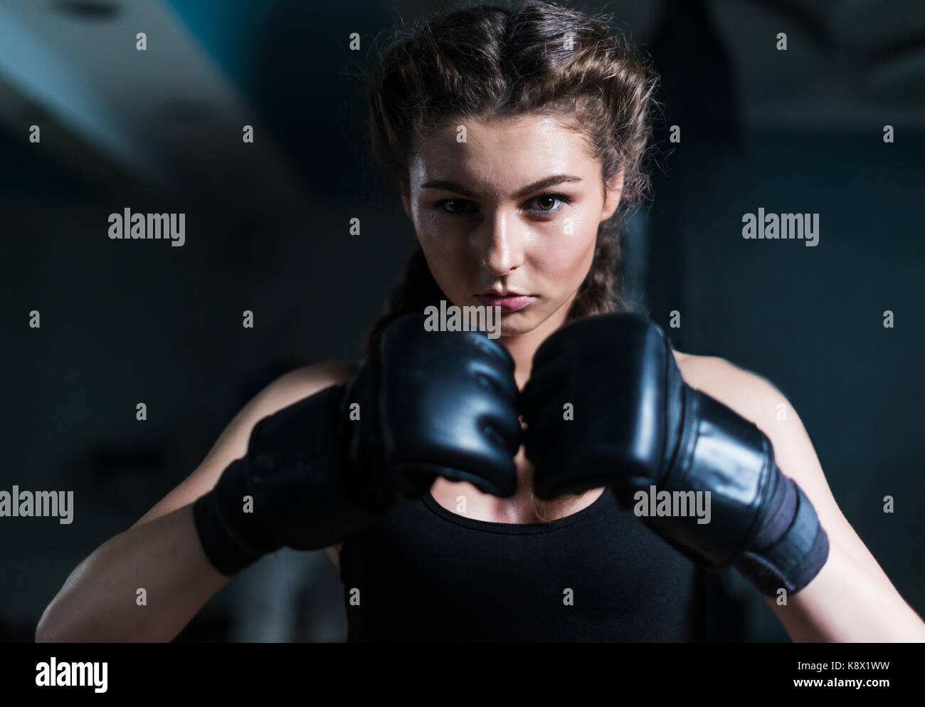 Young fighter boxer girl wearing boxing gloves before training. She is ...