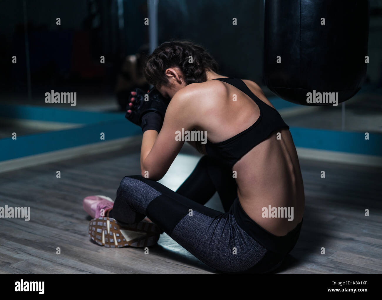 Upset young fighter boxer girl wearing boxing gloves siting on the ...