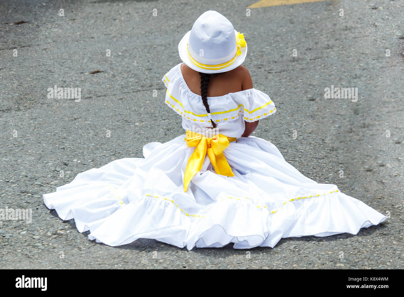 LIttle girl in traditional Costa Rican clothing seated on the street ...