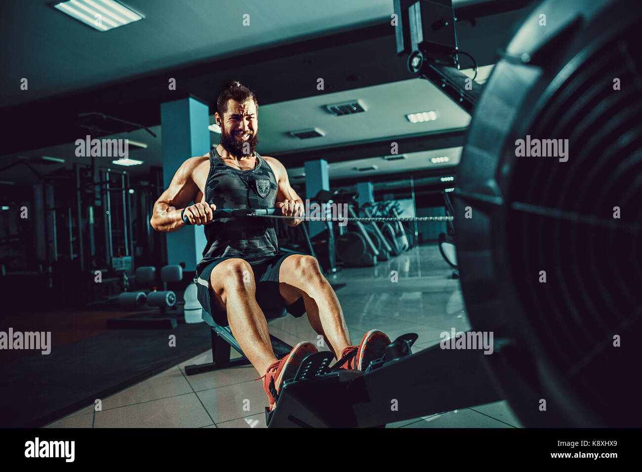 Muscular fit man using rowing machine at gym Stock Photo - Alamy