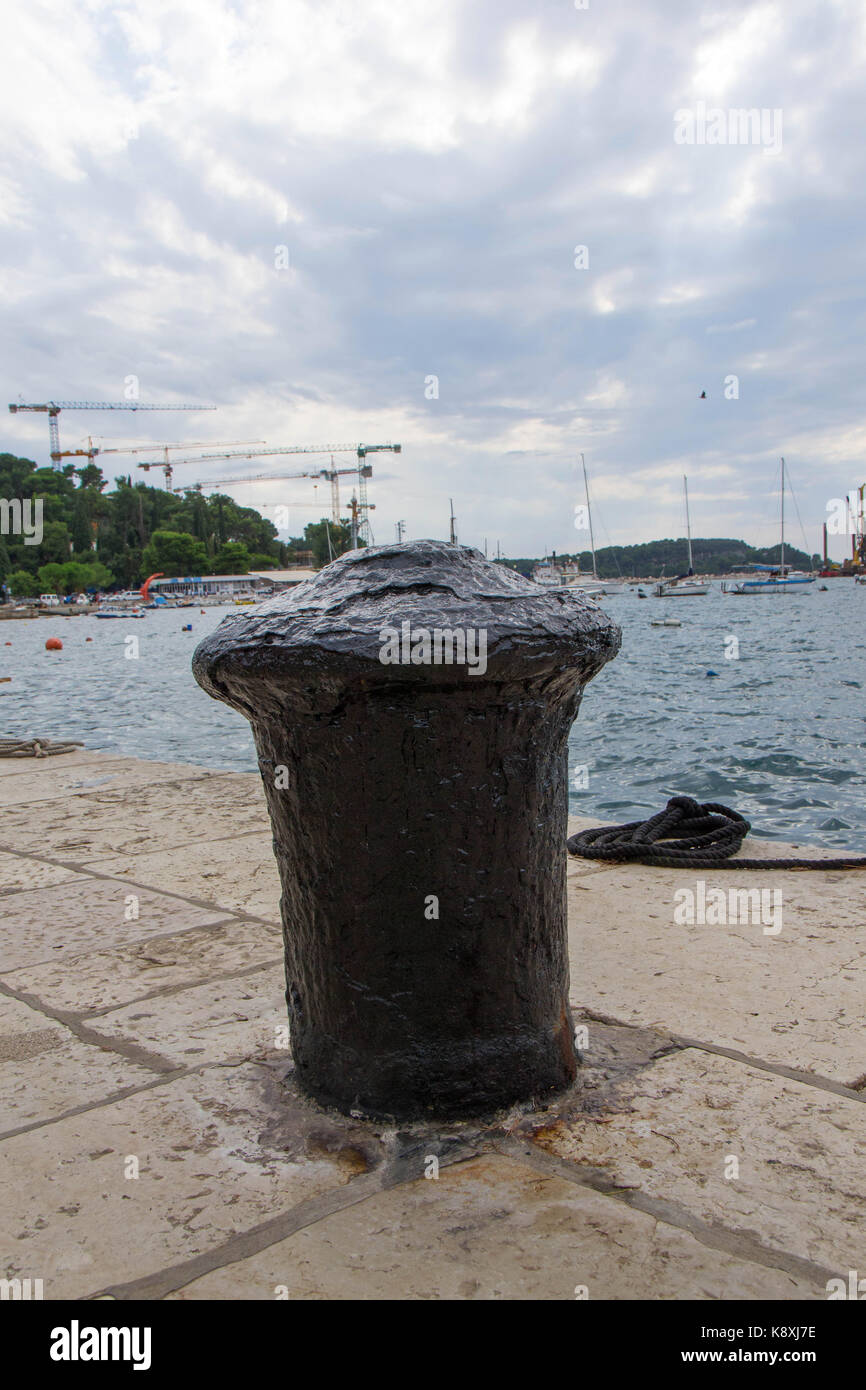 A short, thick post on the deck of a ship or on a wharf, to which a ...