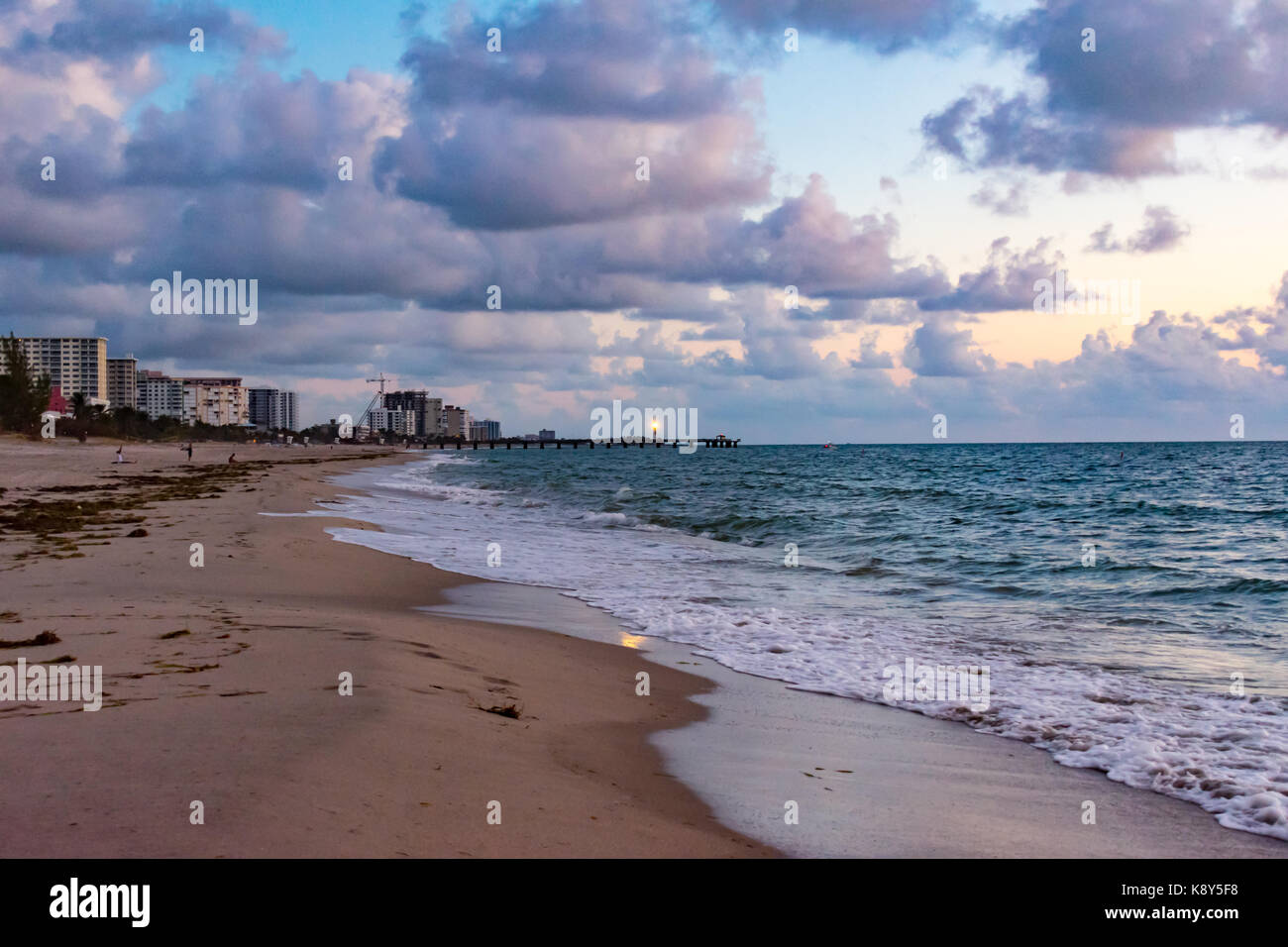 an early morning at the beach with the pier and lighthouse in the ...