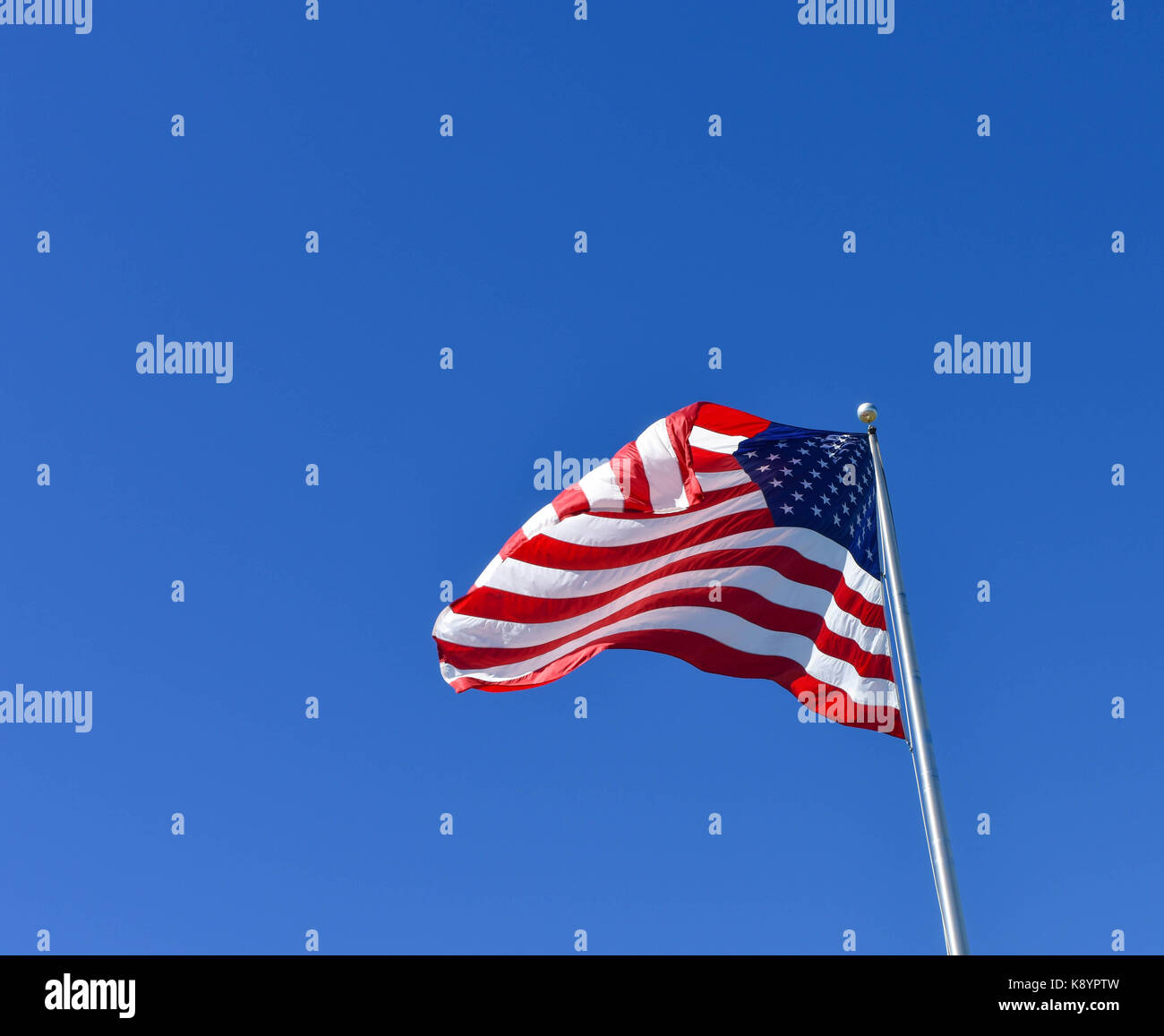 Flapping United States American Flag with clear blue sky background ...