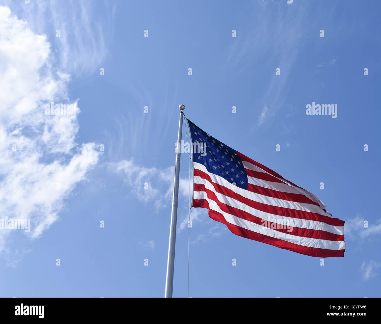 Swirling clouds behind a Large American Flag with sun highlights Stock ...