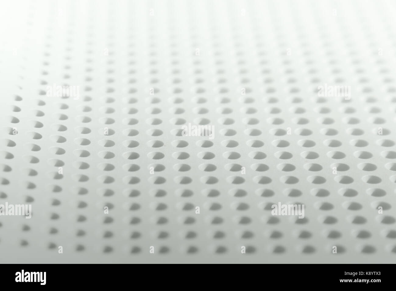 Abstract light colored surface with holes built in a row for creativity ...