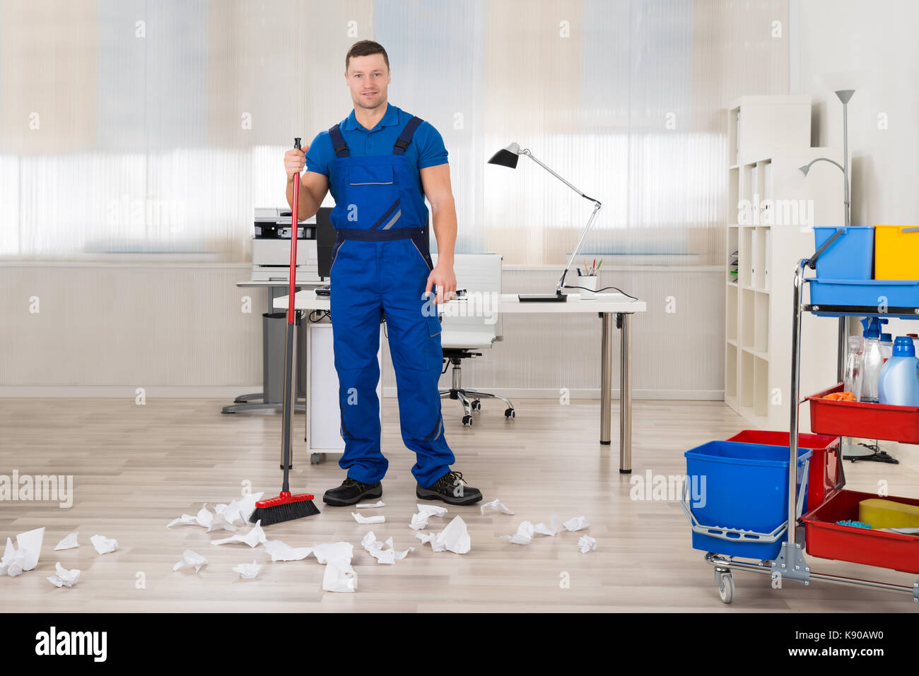 Full length of male janitor cleaning floor with broom in office Stock ...