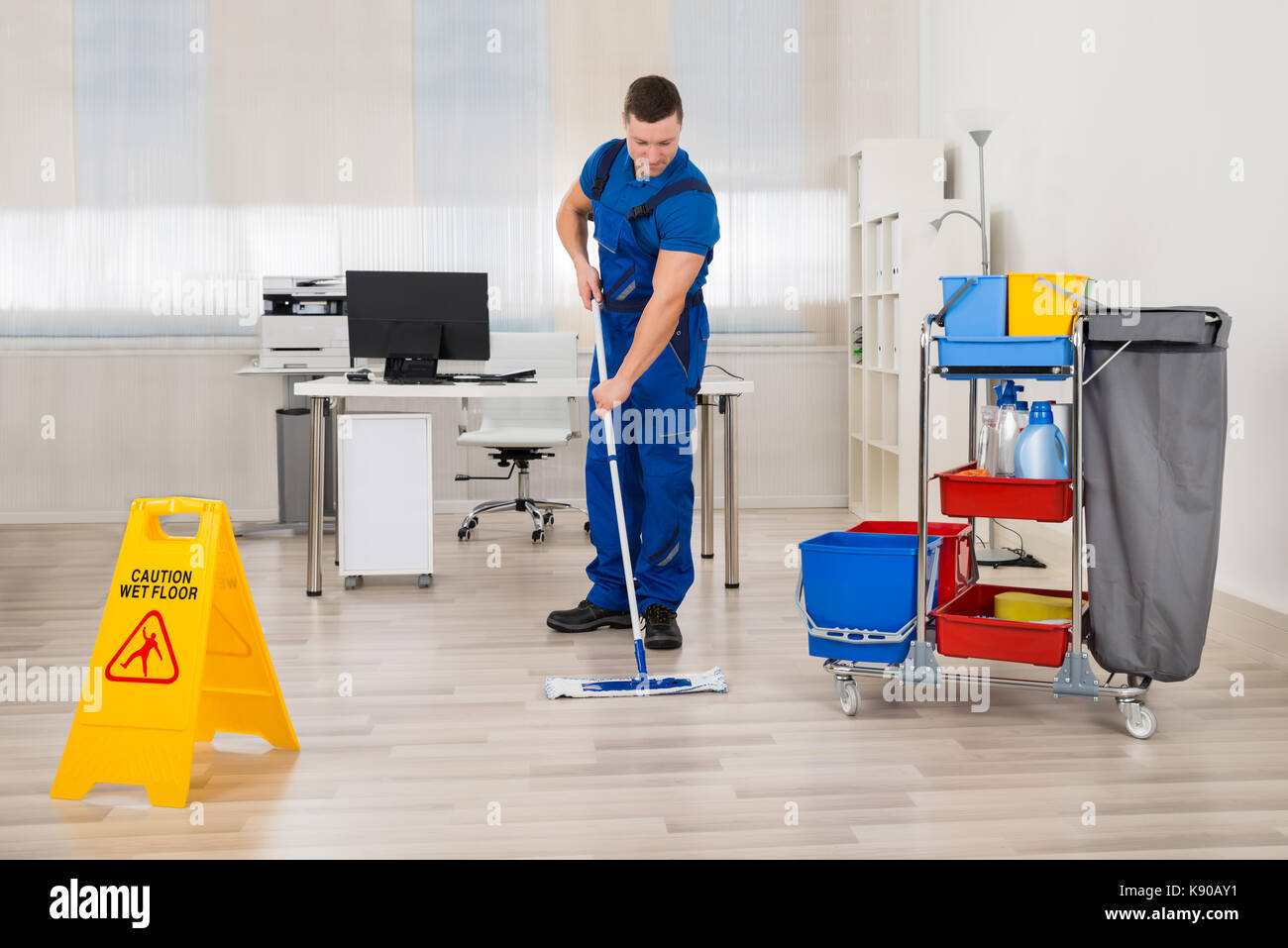 Full length of male janitor mopping floor in office Stock Photo - Alamy
