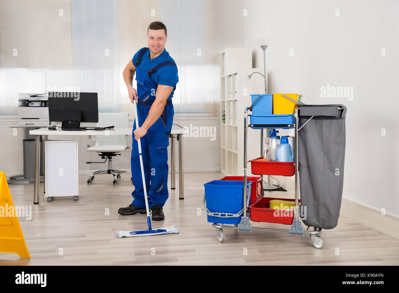 Full length of male janitor mopping floor in office Stock Photo - Alamy
