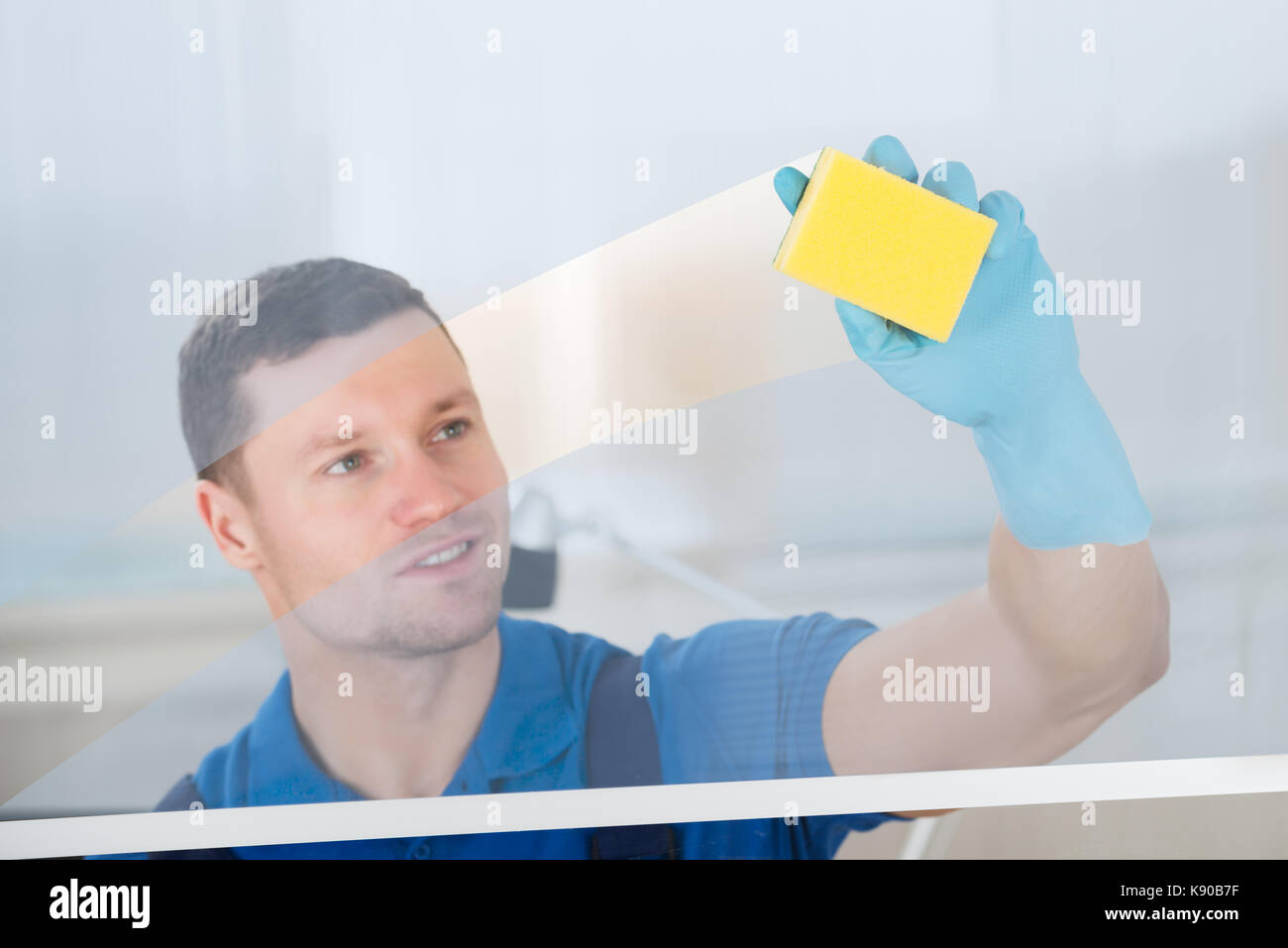 Mid adult male worker cleaning glass window with rag Stock Photo - Alamy