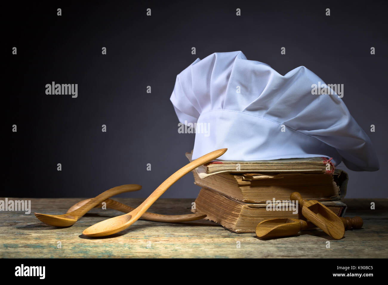 Old culinary books , chef hat and wooden spoons . Kitchen accessories ...
