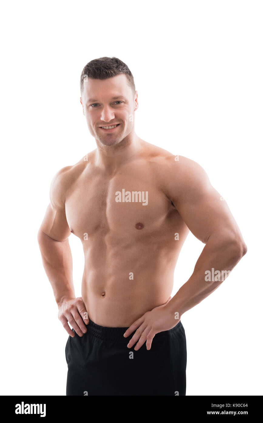 Portrait of happy muscular man standing with hands on hip against white ...