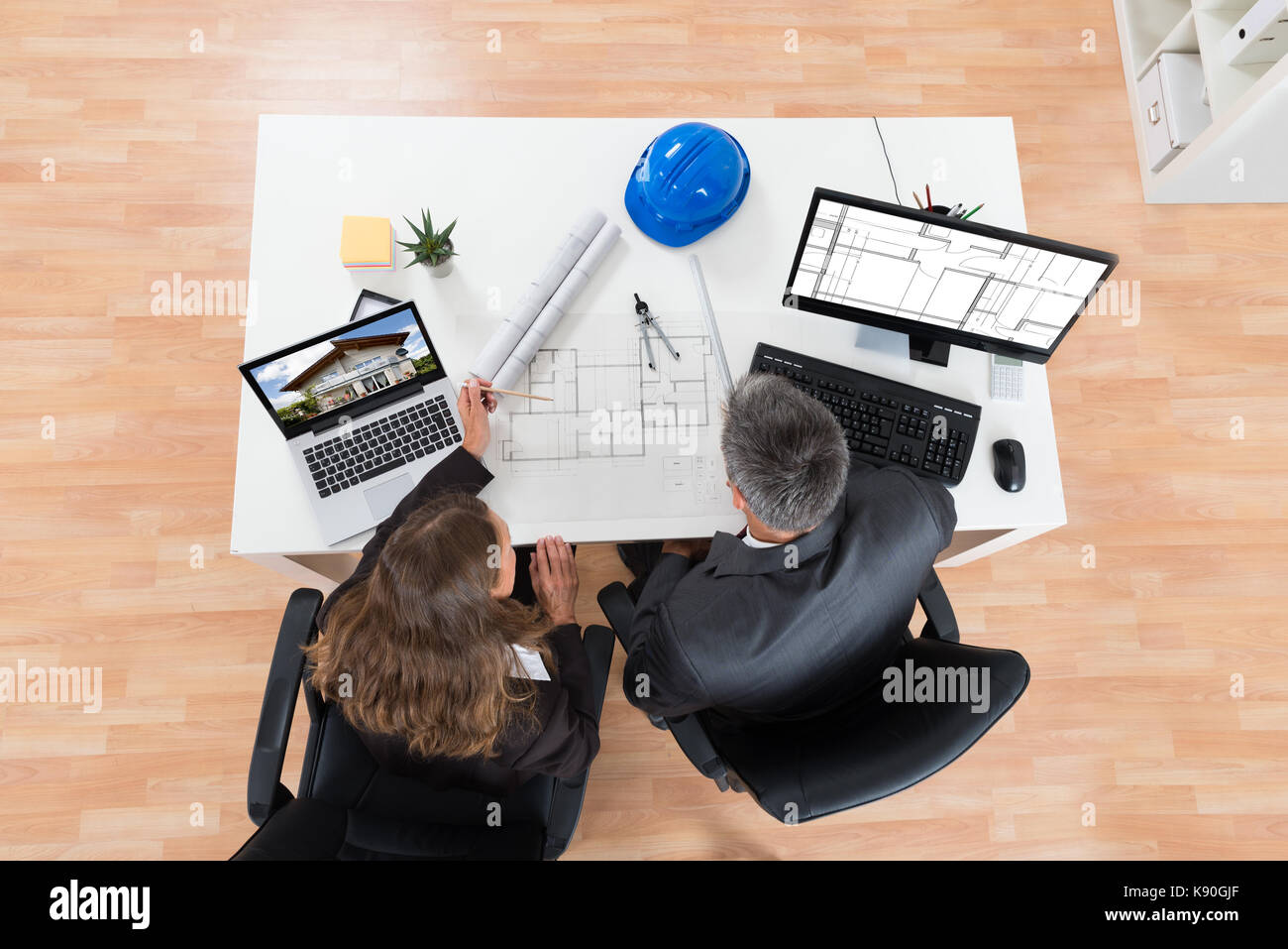 High Angle View Of Two Architects Discussing Blueprint In Office Stock ...
