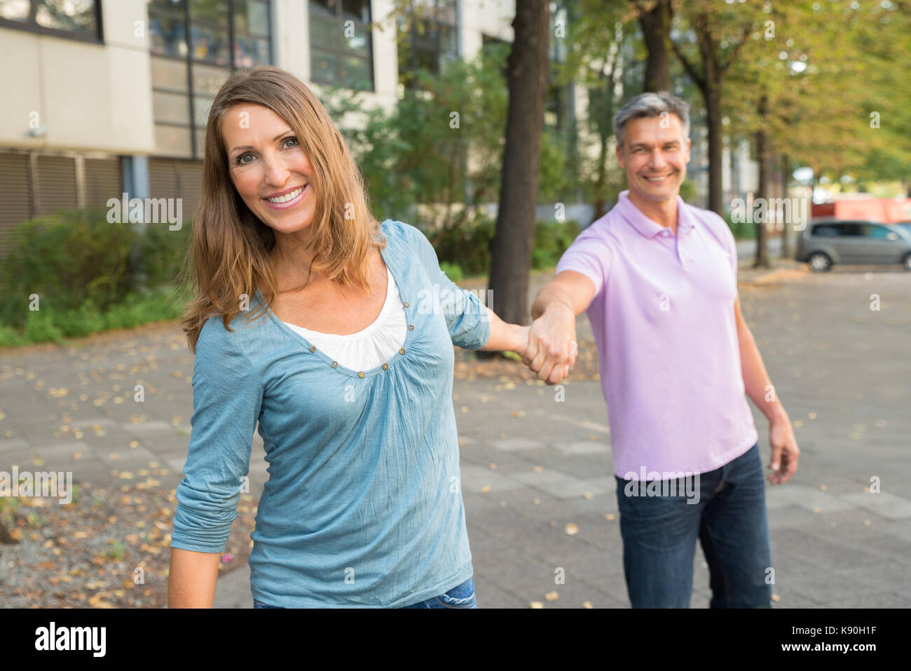 Happy Mature Man Pulling Woman In The Street Stock Photo - Alamy