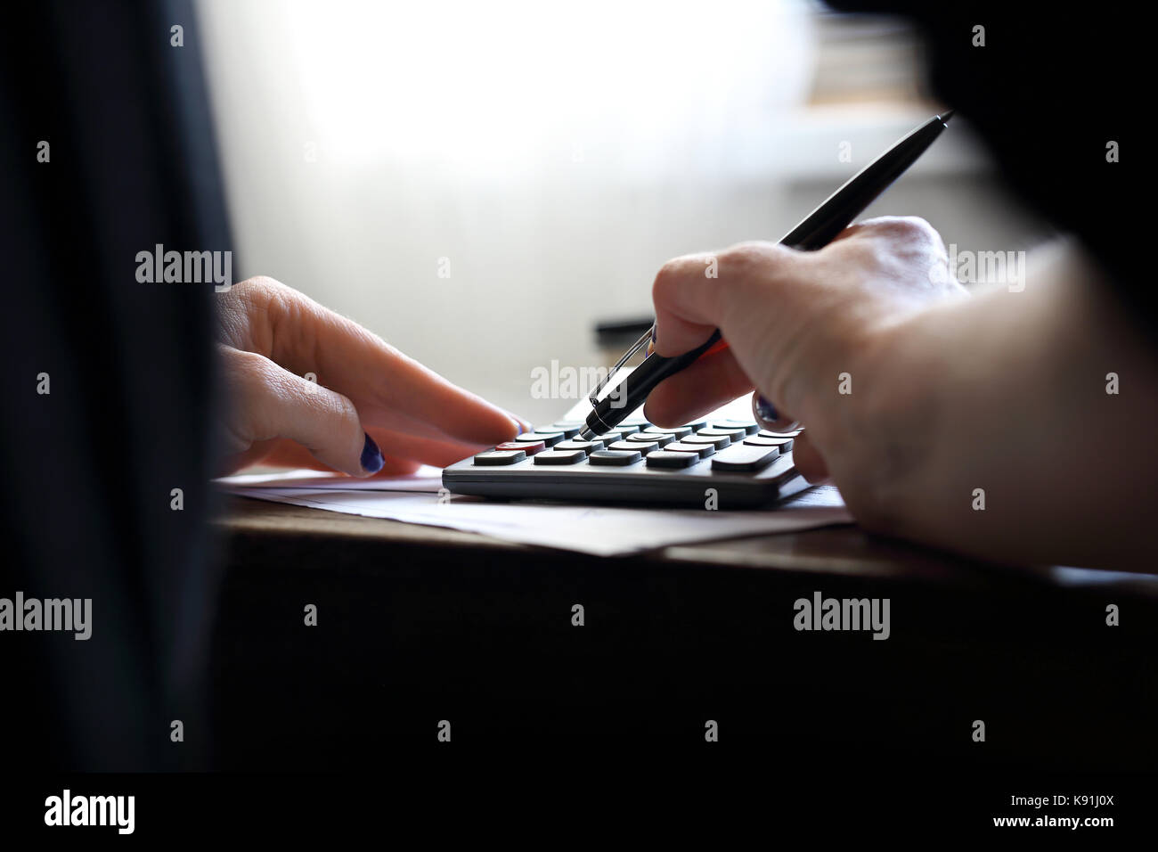 Money. Counting on the calculator Stock Photo - Alamy