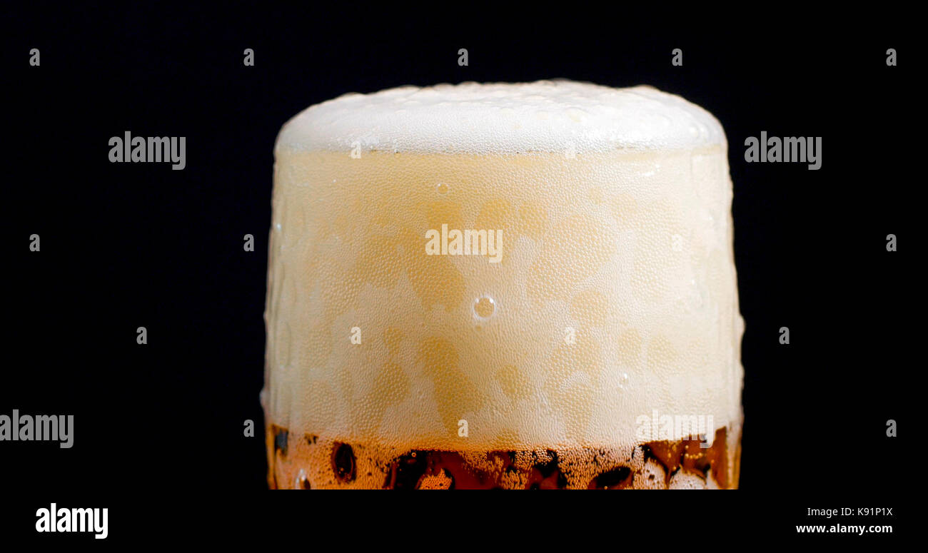 lager beer on a pint glass with black background Stock Photo - Alamy