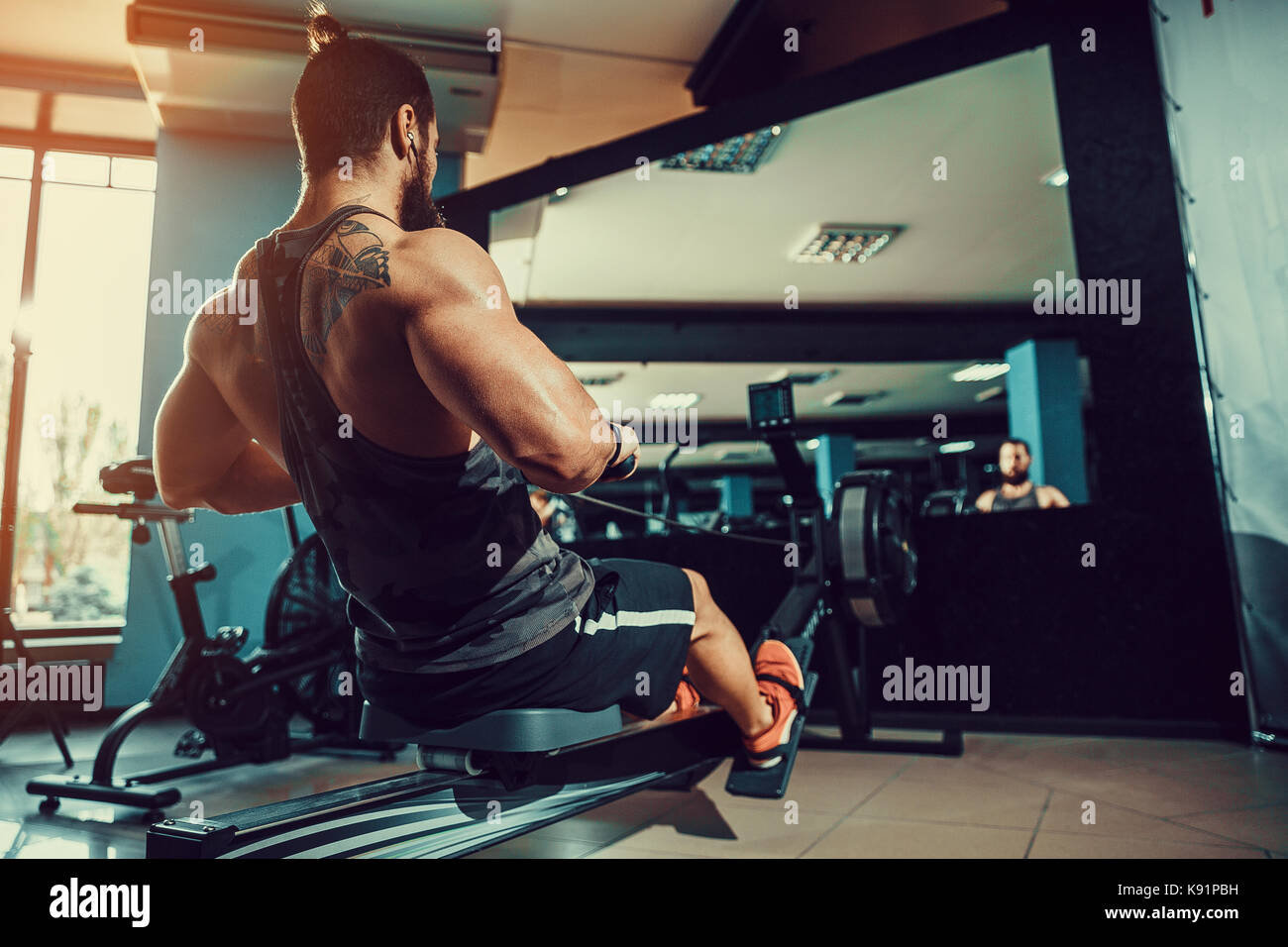 Muscular fit man using rowing machine at gym Stock Photo - Alamy